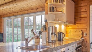Cozinha com bancada de granito, eletrodomésticos de aço inoxidável e janela com vista para uma paisagem verde.