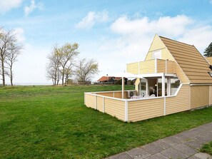 Uma casa moderna com um amplo deck, área de estar coberta ao ar livre e vista para o mar.