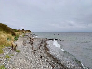 Um caminho costeiro com pedras e grama, que se estende até o mar.