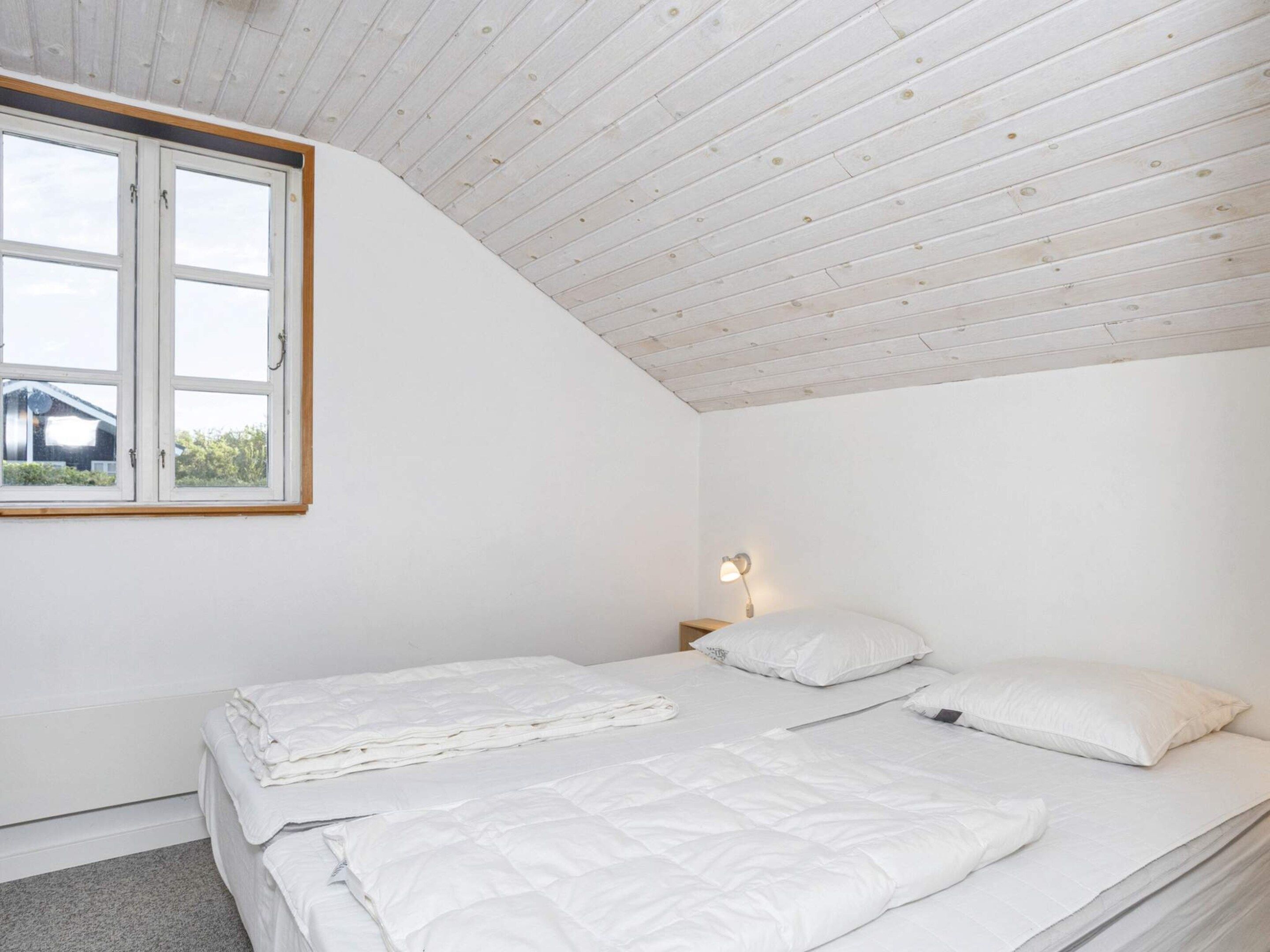 Quarto com cama, janela e luminária na parede.