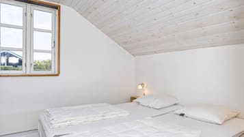 Quarto com cama, janela e luminária na parede.