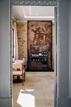 Um quarto com uma mesa de jantar, cadeiras, uma adega com garrafas e uma parede texturizada.