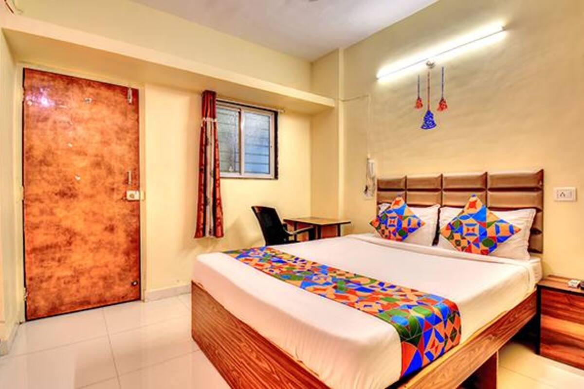 Um quarto com cama, escrivaninha, cadeira e janela.