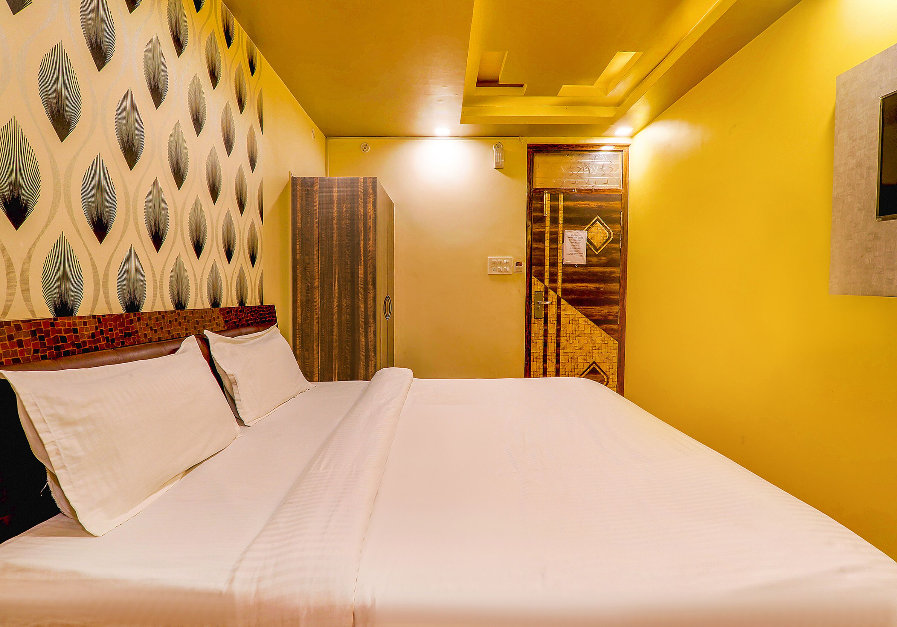 Quarto de hotel com uma cama grande, parede estampada e porta de madeira.