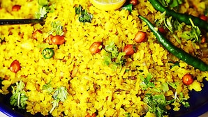 Um prato de arroz amarelo com amendoins, pimentas verdes e uma fatia de limão.