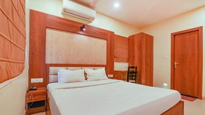 Quarto de hotel com uma cama grande, cabeceira de madeira e um guarda-roupa.