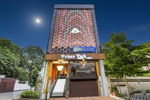 Um hotel alto com fachada hexagonal e um letreiro com 'Prince Park' e 'fabHOTELS'.