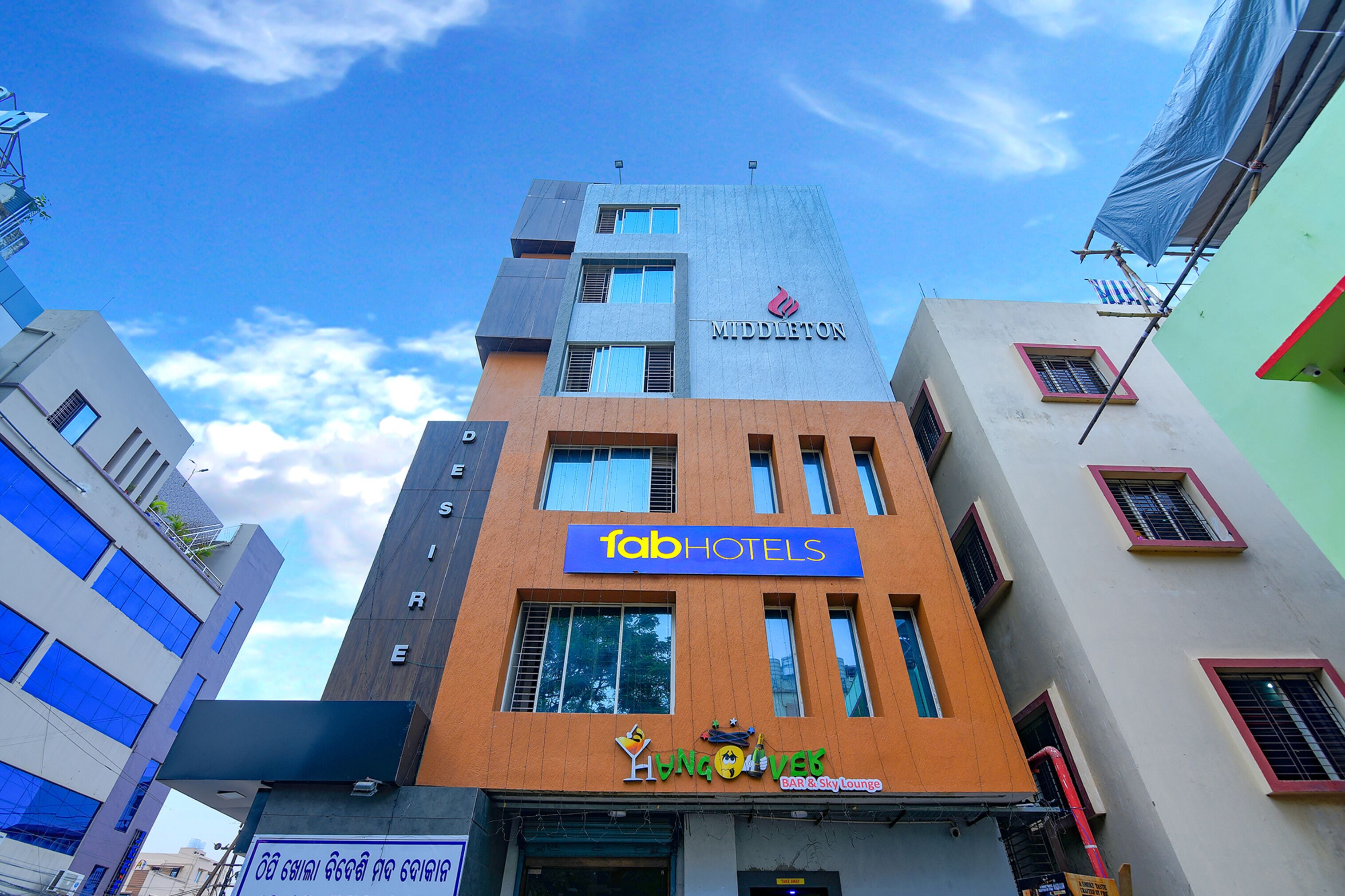 Um edifício com vários andares, com a placa 'fab hotels', a placa 'Middleton' e um bar 'Jungle Juice'.