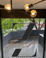 Um interior moderno com um padrão geométrico no chão, uma grande obra de arte abstrata na parede e luminárias pendentes.