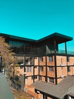 Um edifício moderno com fachada de vidro, níveis inferiores de tijolo e telhado plano.