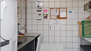 Cozinha com geladeira branca, pia, lava-louças e um mural com diversos avisos.