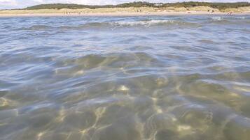 Uma praia com água cristalina e um litoral distante.
