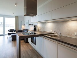 Uma cozinha moderna com uma ilha central, eletrodomésticos de aço inoxidável e uma grande janela com vista para a cidade.