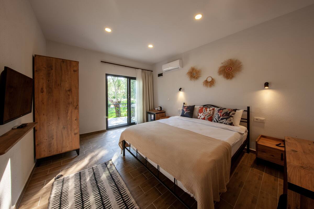 Quarto com uma cama grande, guarda-roupa de madeira, televisão e porta de vidro deslizante para o exterior.