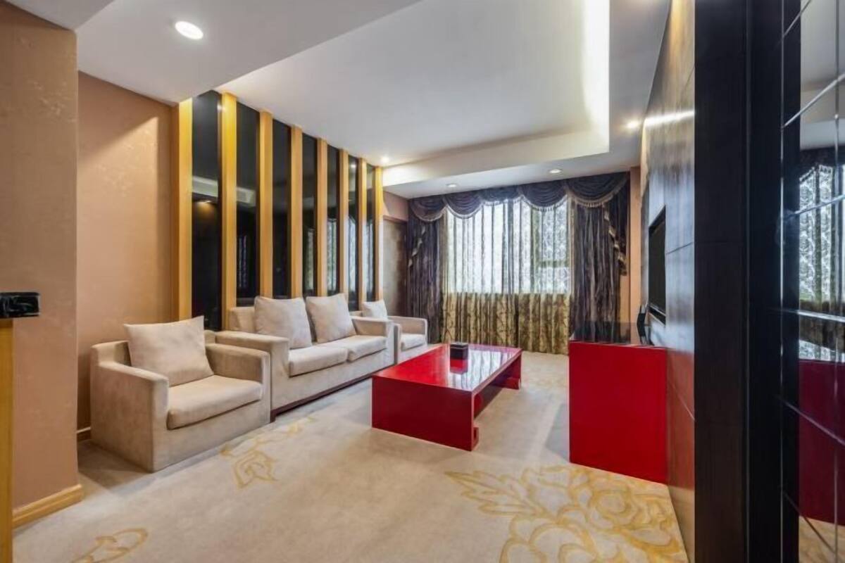 Uma sala de estar moderna com um sofá, uma mesa de centro vermelha e um tapete estampado.