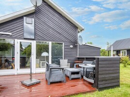 Uma casa com varanda, móveis de jardim e antena parabólica.