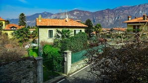 Um bairro residencial com muros de pedra, cerca verde e casas com telhados de telha vermelha.