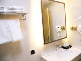 Casa de banho de hotel com lavatório, porta-toalhas e dois secadores de cabelo.
