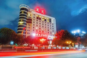 Um hotel de vários andares com uma placa vermelha destacada, fachada bem iluminada e design arquitetônico moderno.