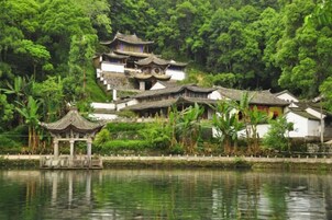 Um complexo tradicional de construções chinesas, incluindo uma pagode, localizado às margens de um corpo d'água.