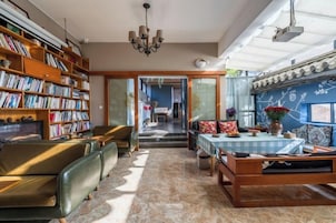 Uma sala de estar ampla com uma grande estante de livros, uma mesa de jantar e um confortável espaço de estar.