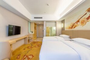 Quarto de hotel com cama, televisão, escrivaninha e banheiro.