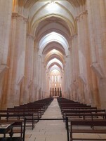 Interior de uma catedral, com fileiras de bancos e uma nave central que leva a um altar.