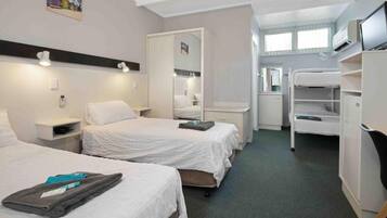 Quarto de hotel com duas camas, um guarda-roupa, uma secretária e uma televisão.