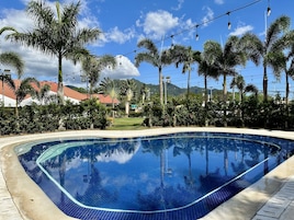 Piscina rodeada por palmeiras e um cenário montanhoso.