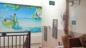 Quarto com um mural de um barco na água, um sinal de saída de incêndio, um vaso com galhos e um quadro na parede.