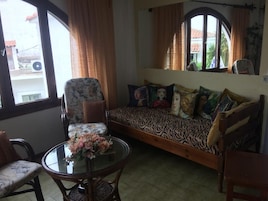Quarto com sofá, mesa redonda com um arranjo floral e uma cadeira.