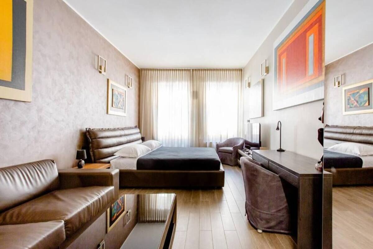 Quarto de hotel com cama, sofá, escrivaninha e cadeira.