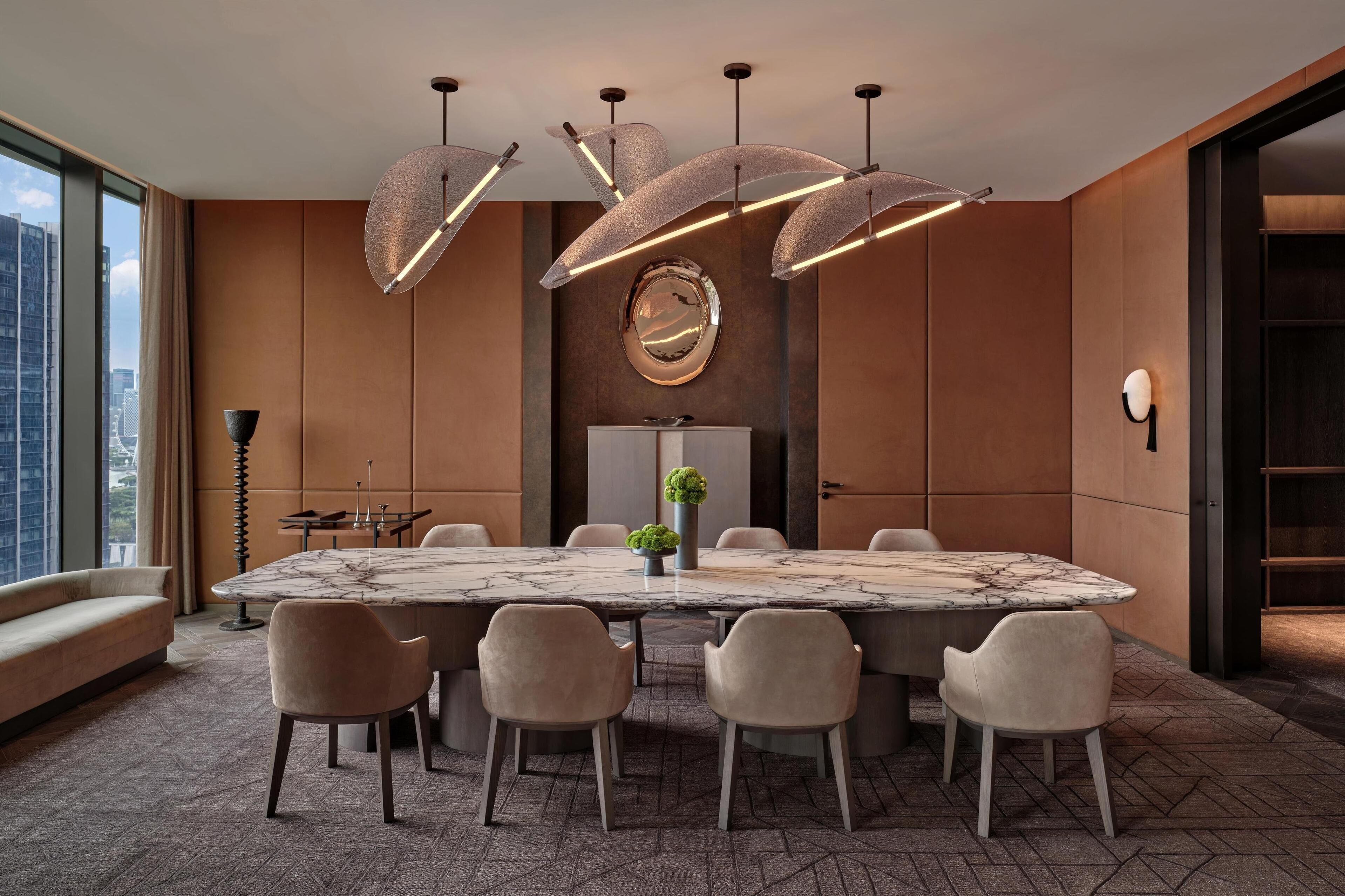 Uma sala de conferências moderna com uma mesa de mármore, cadeiras bege e um lustre de design exclusivo.