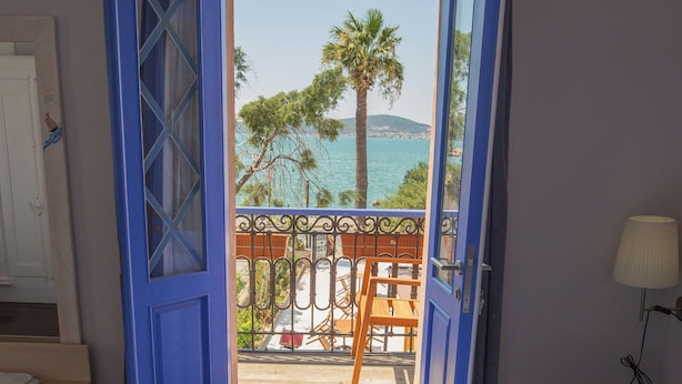 Quarto de hotel com cama, vista para o mar e varanda com mesa e cadeiras.