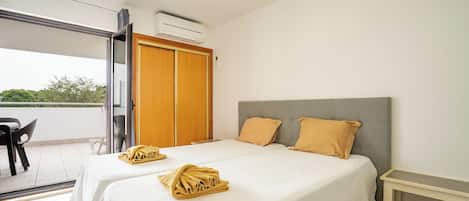 Quarto de hotel com duas camas, uma varanda e unidade de ar condicionado.