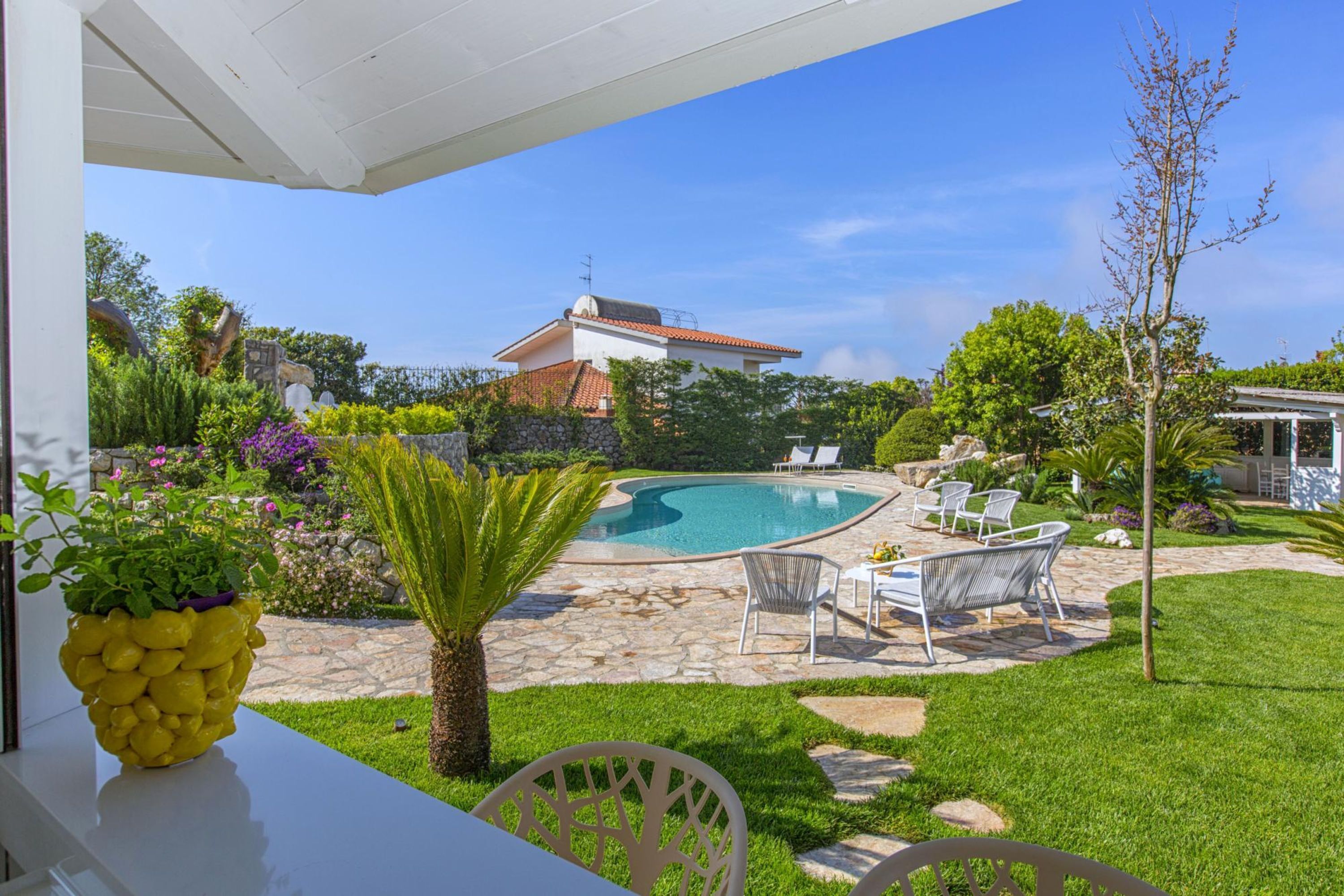 Um quintal com piscina, móveis de exterior e um caminho de pedra.