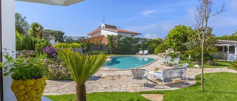 Um quintal com piscina, móveis de exterior e um caminho de pedra.