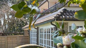 Uma casa tradicional com telhado de telhas, uma ponte de pedra e uma cerca de madeira.