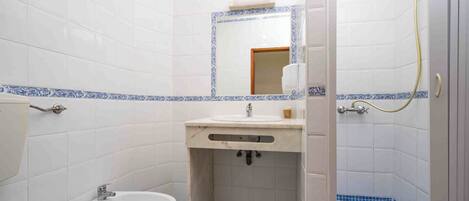Um banheiro com vaso sanitário, pia e chuveiro.