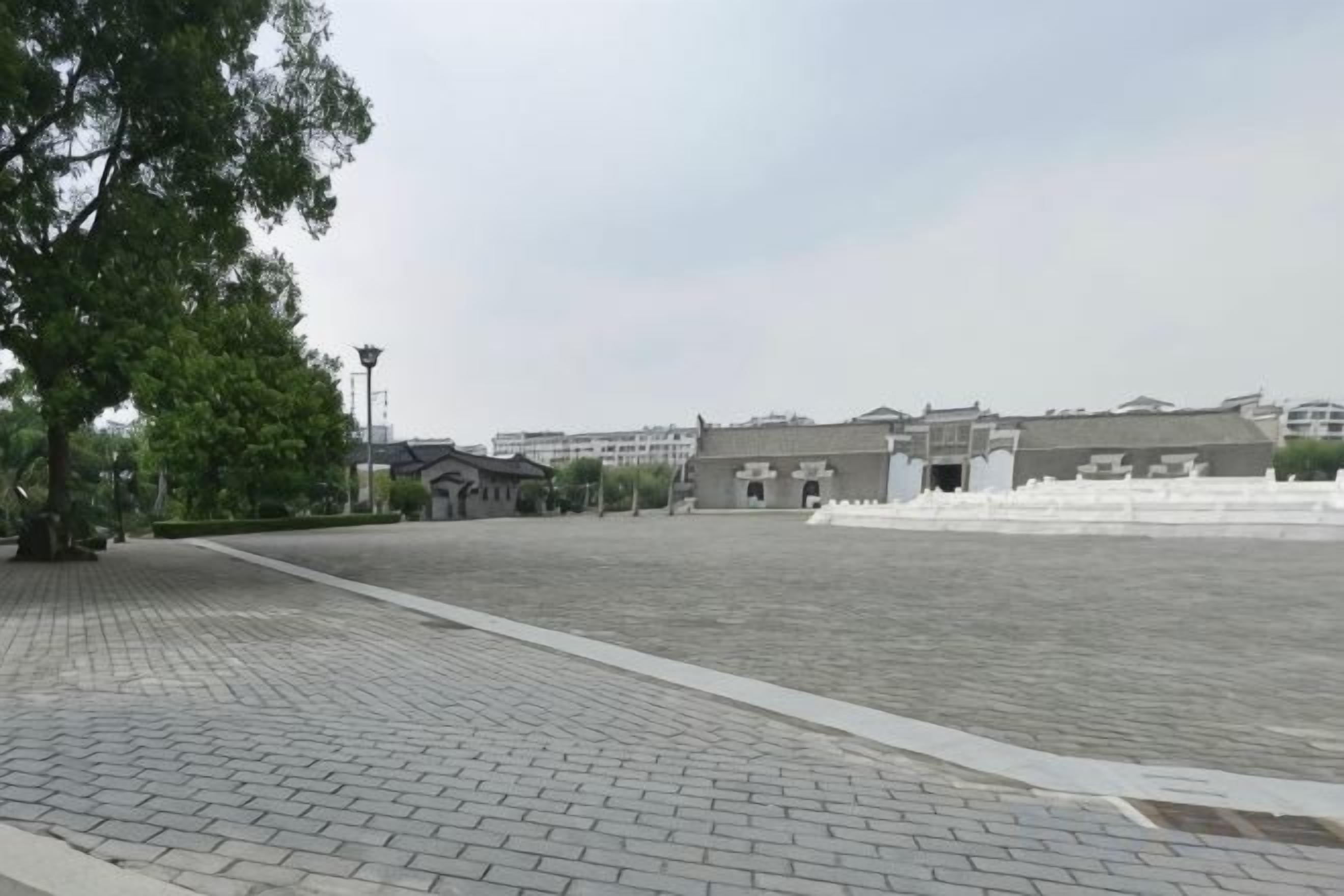 Um pátio pavimentado com um edifício ao fundo.