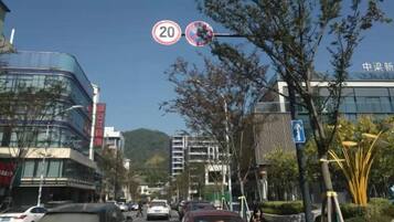 Rua com edifícios, carros e placa de limite de velocidade.