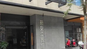 Entrada de um edifício moderno com uma grande placa em caracteres chineses.