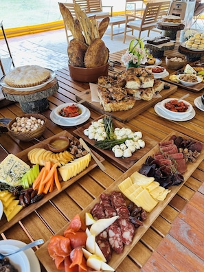 Uma mesa de madeira com diversos alimentos, incluindo queijos, carnes e pão.