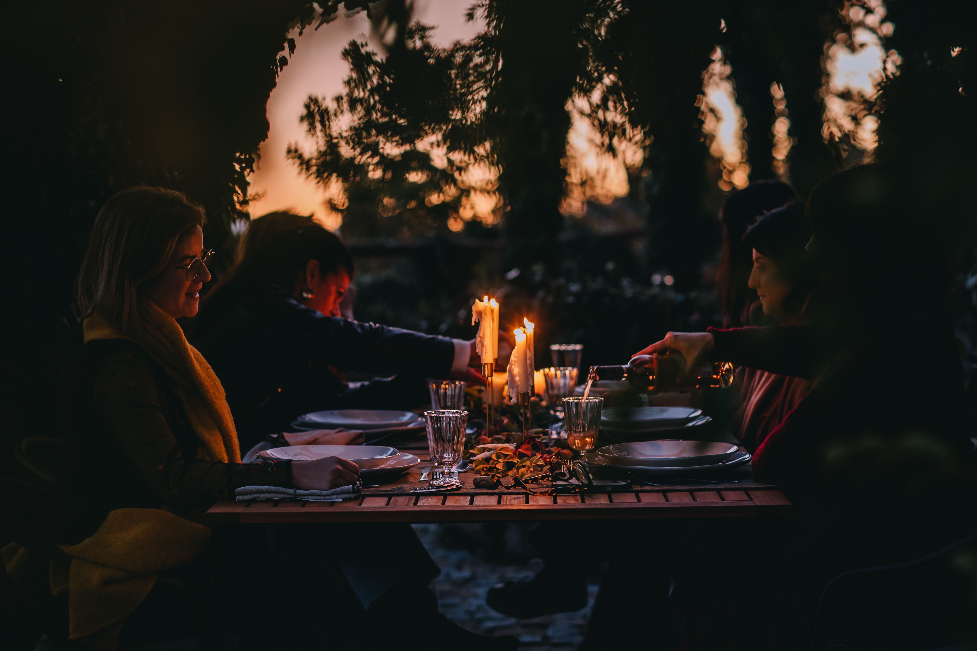 Mesa posta para quatro pessoas, com velas, copos e pratos.