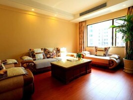 Quarto de hotel com sofá, mesa de centro e uma grande janela com vista para edifícios.
