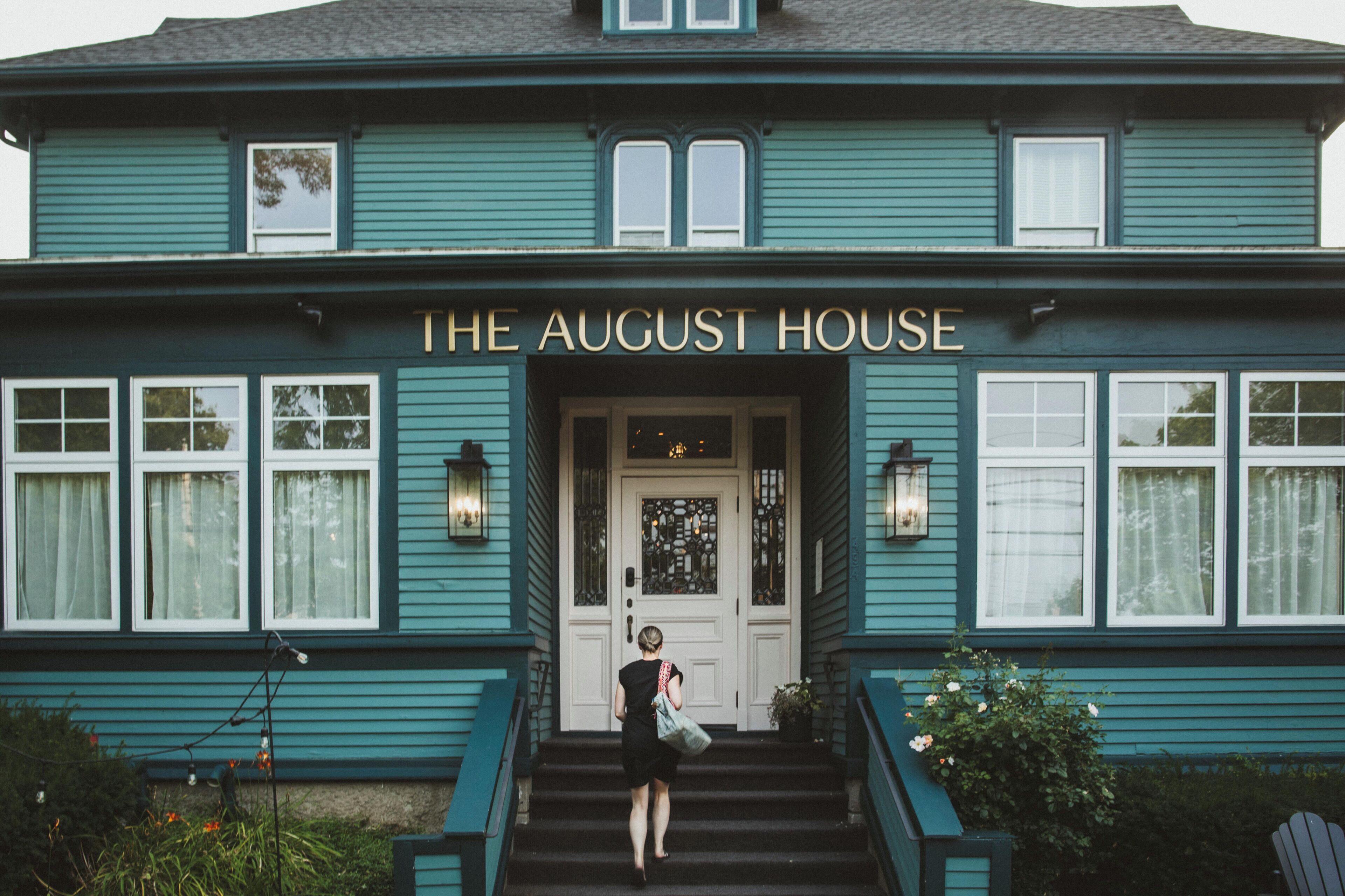 Um edifício de dois andares com a placa 'The August House' sobre a entrada.