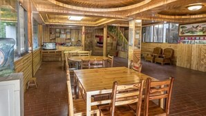 Interior em madeira com uma mesa de jantar central, cadeiras e uma escada.