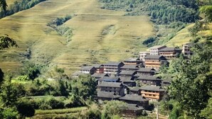 Uma vila na encosta com campos em socalcos e edifícios tradicionais.