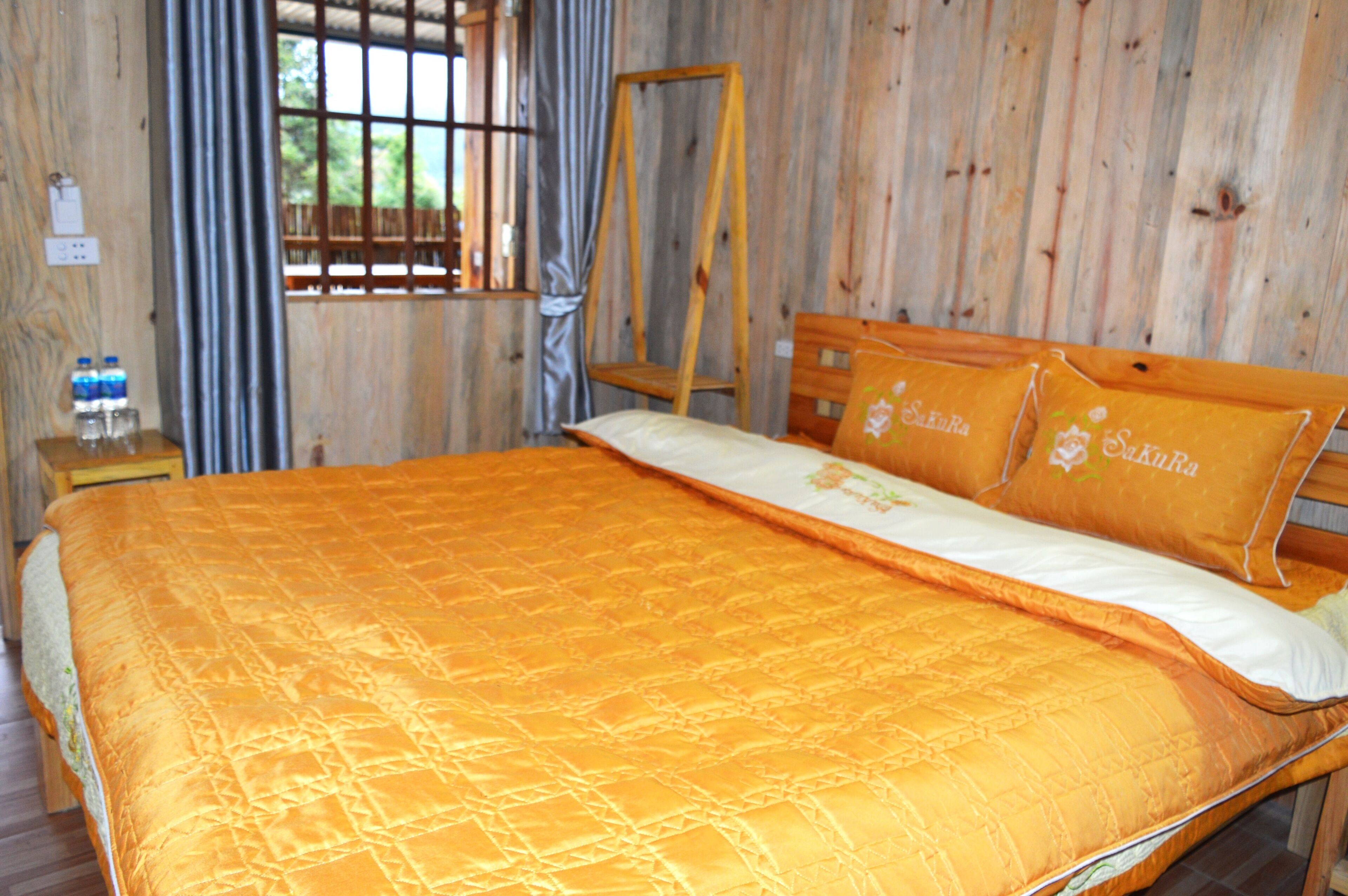 Quarto de madeira com uma cama, uma escada de madeira e uma mesa de cabeceira com garrafas de água.