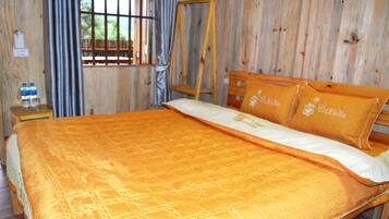 Quarto de madeira com uma cama, uma escada de madeira e uma mesa de cabeceira com garrafas de água.
